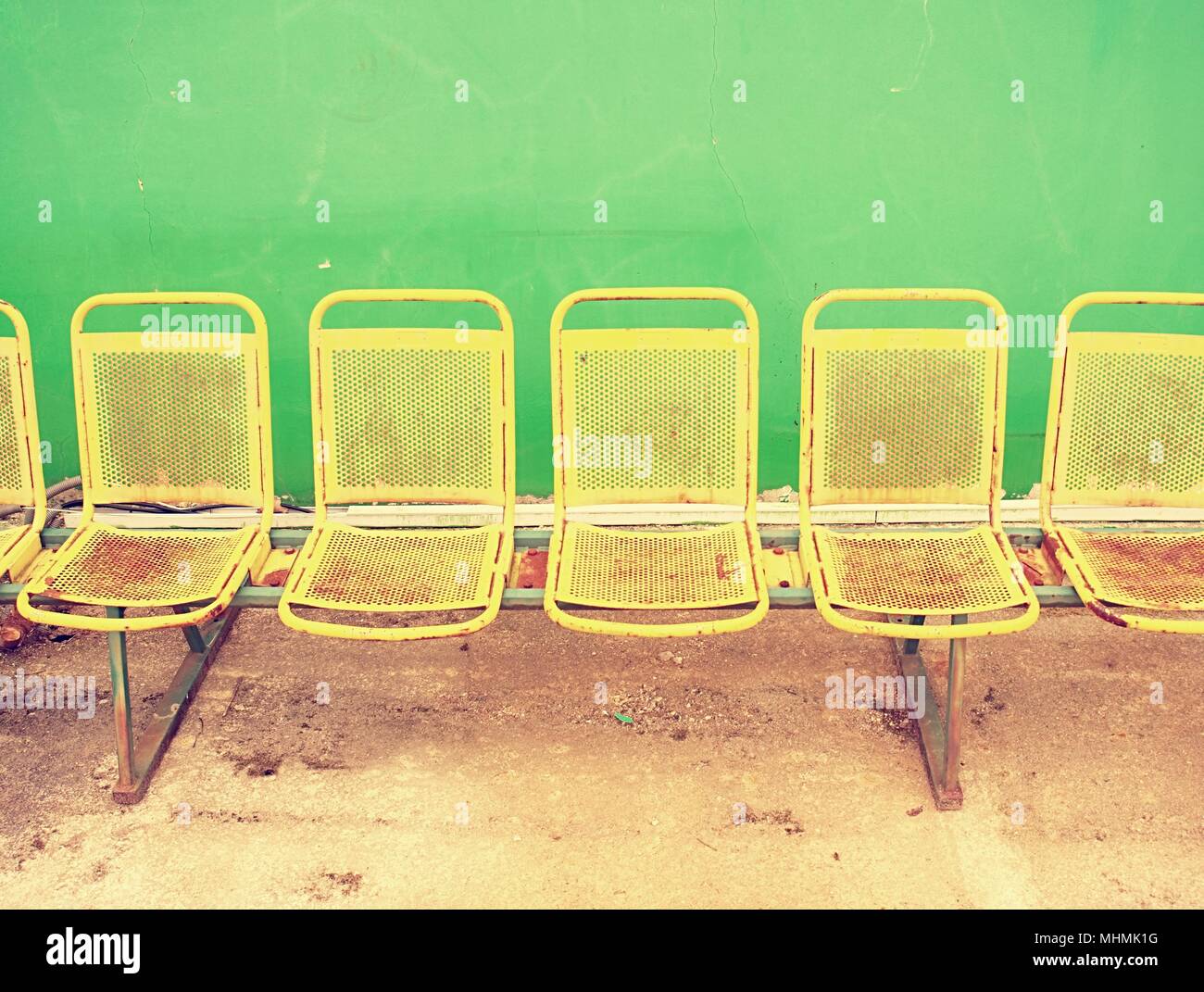 Old yellow rusty metal seats on outdoor stadium. Players bench chairs ...
