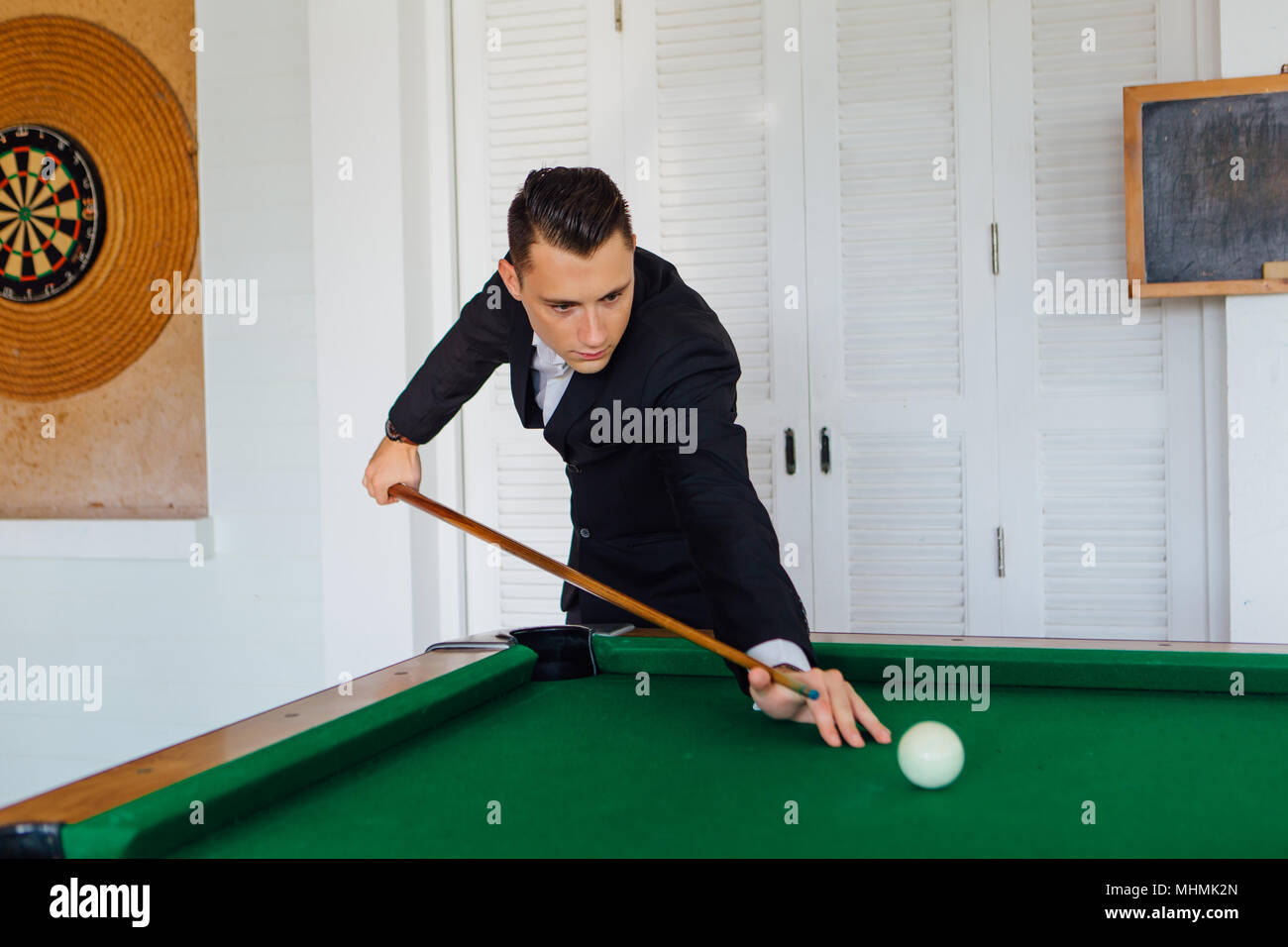 Young handsome man dressed in classic costume playing billiard game ...
