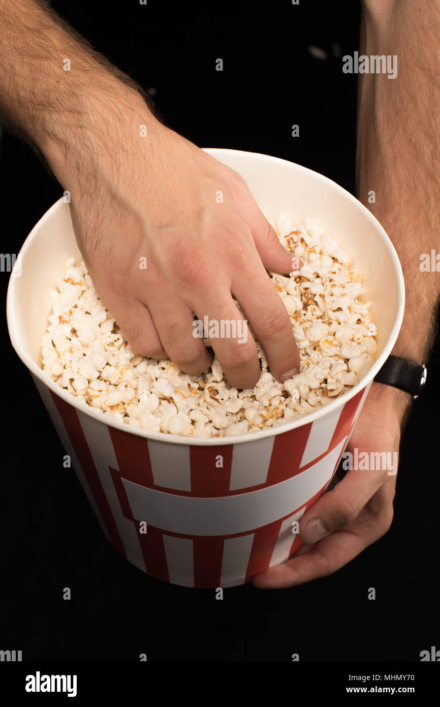 man taking popcorn out of bucket Stock Photo - Alamy