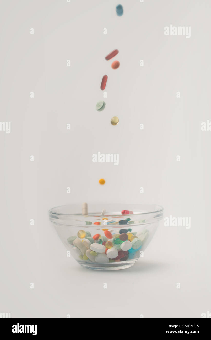 Pills falling into glass bowl Stock Photo - Alamy