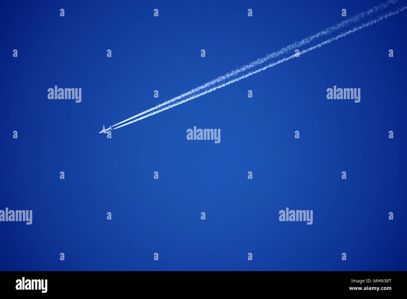 Jet Airplane trails tracks chemtrails in the deep blue sky background ...