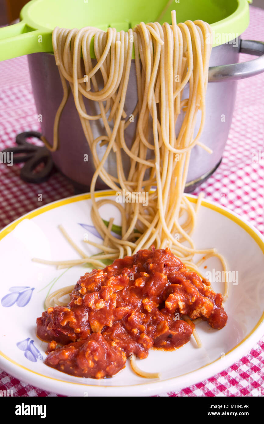 spaghetti that sticks out of a colander near a dish of tomato sauce ...