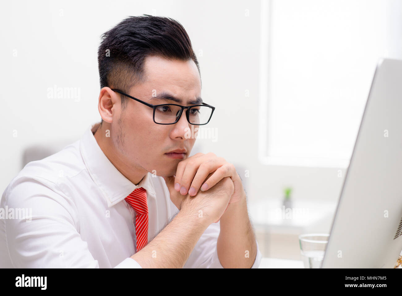 Young stylish worker at office working with computer and thinking how ...