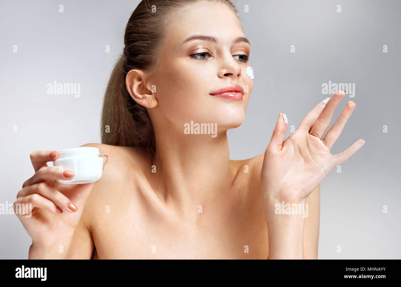 Gorgeous woman with moisturizing cream on her face. Photo of woman with ...