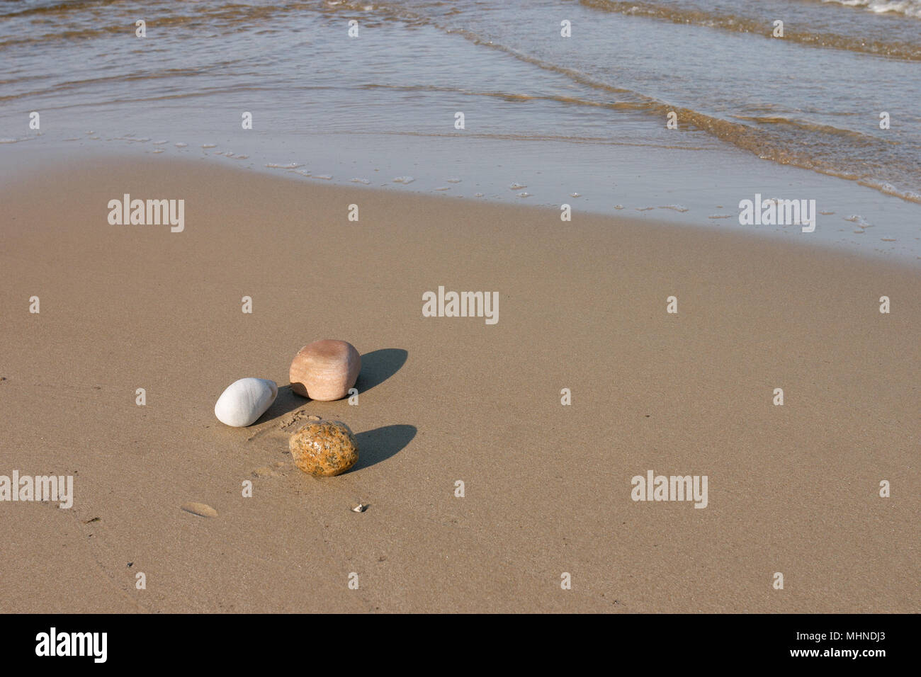 Three rocks at the shoreline inspires tranquility Stock Photo - Alamy