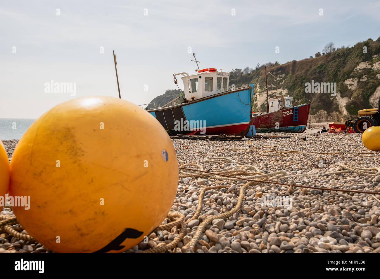 Traditional fishing boats pulled up on a pebble beach for safety with ...