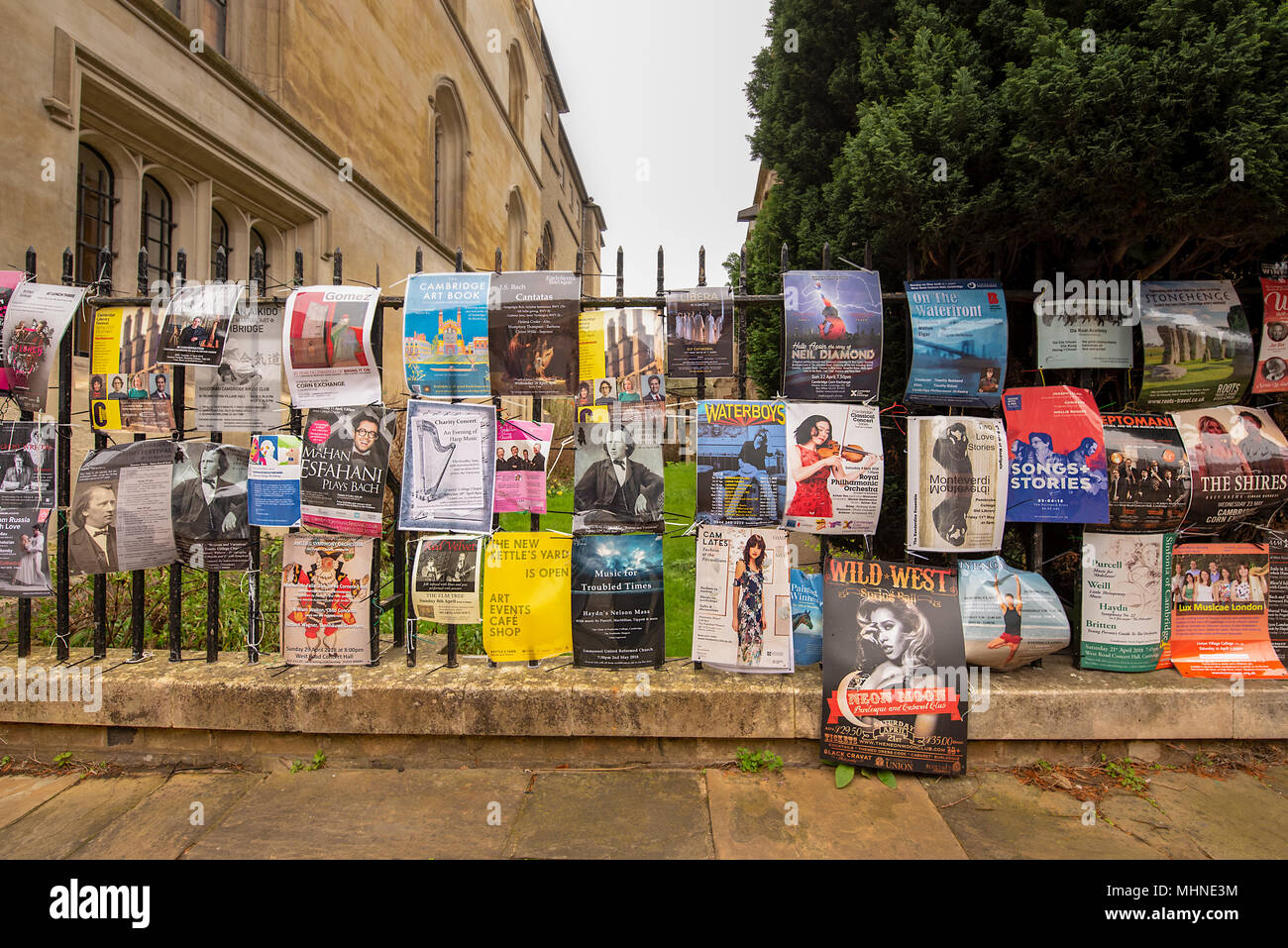 An iron railing fence covered in colourful flyers and posters promoting ...