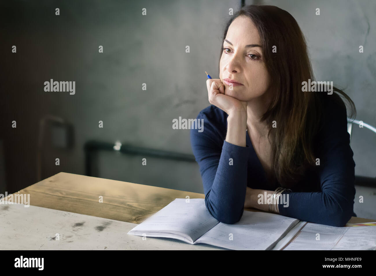 Adult woman sitting alone on a table, thinking, concerned, holding a ...