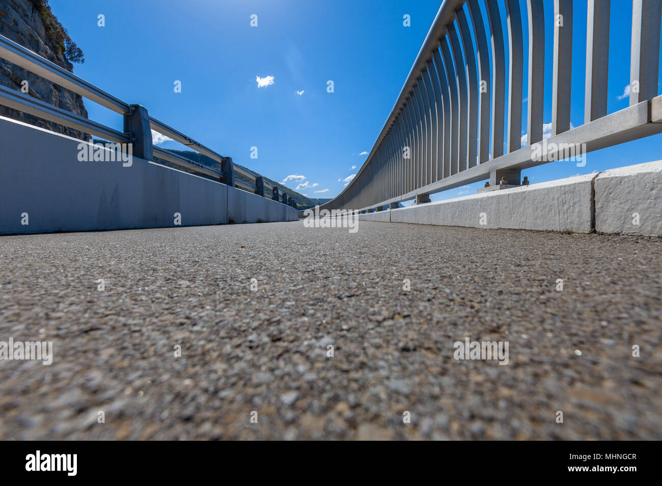 Low angle shot of curved footpath with metal railing Stock Photo - Alamy