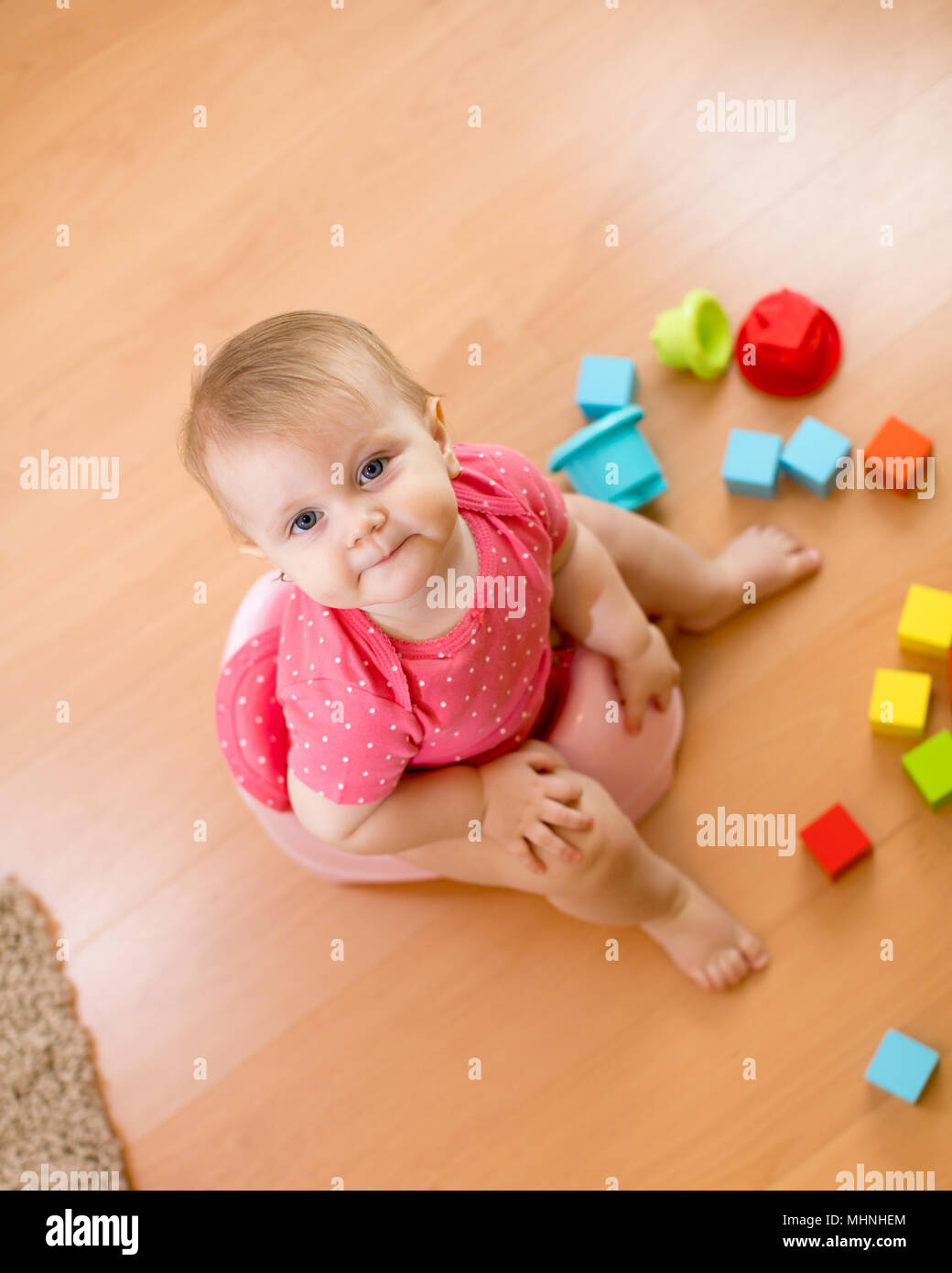 Baby sitting on chamber pot and playing with toys. Top view Stock Photo ...