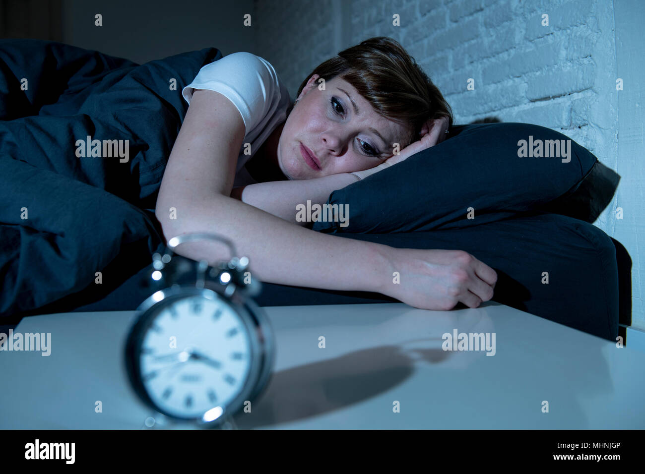 Young attractive red haired caucasian woman lying in bed late at night ...