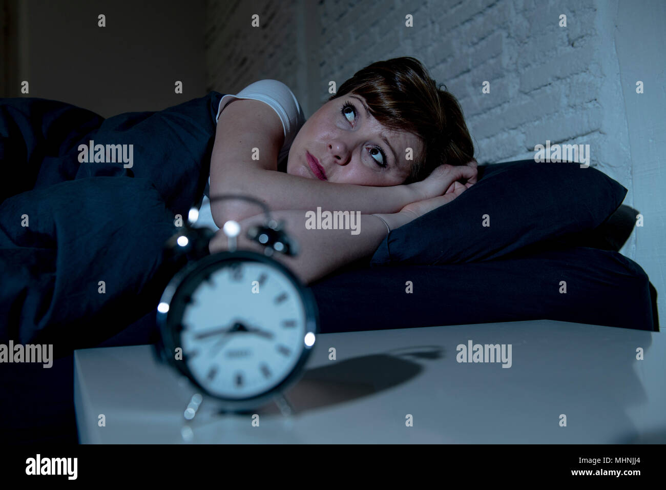 Young attractive red haired caucasian woman lying in bed late at night ...