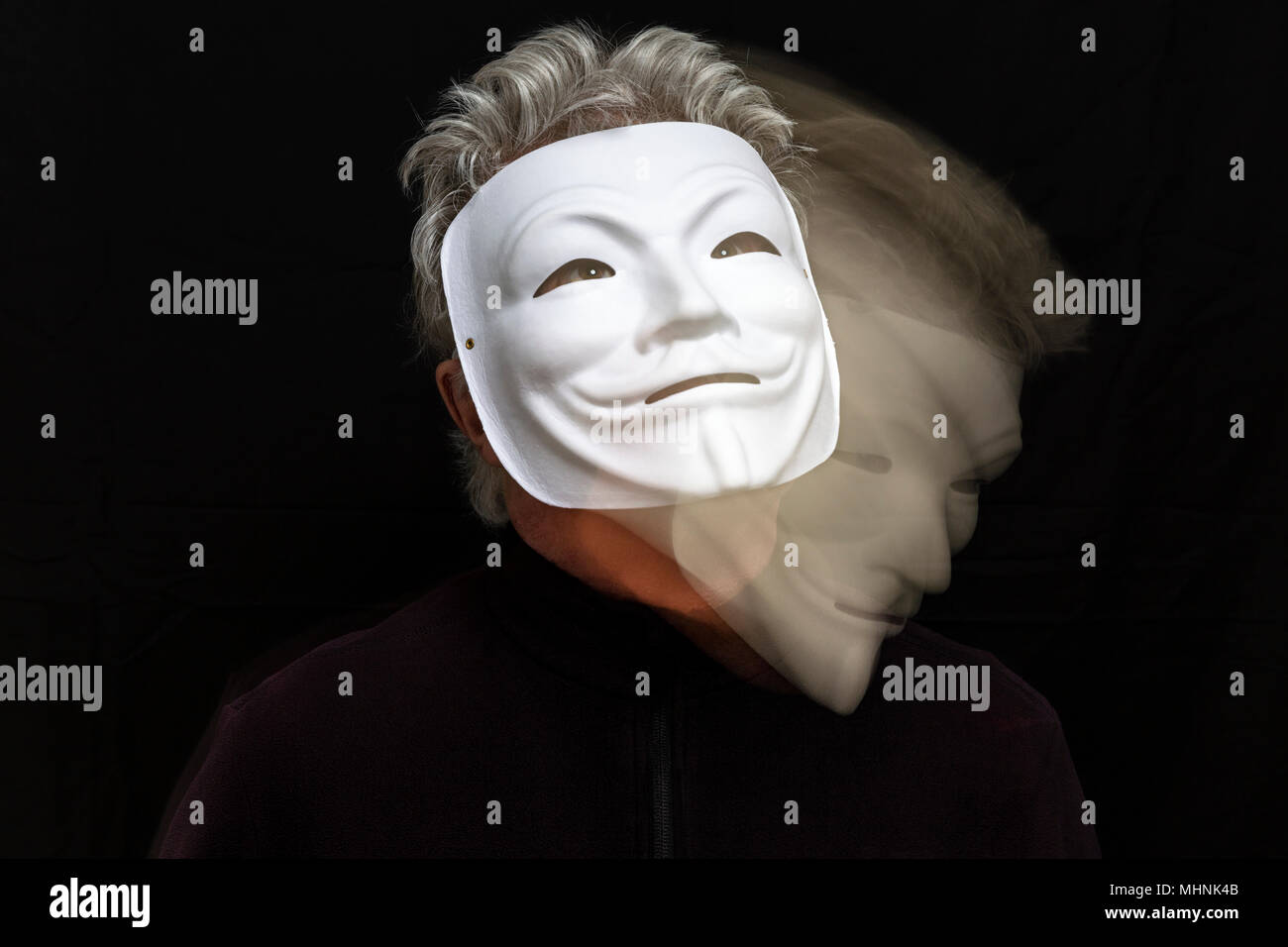 Masked man, moving head to look up and down, slow exposure allowing ...