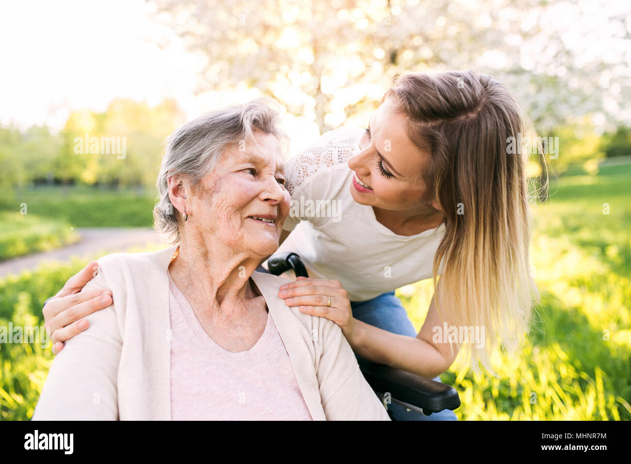Elderly grandmother in wheelchair with granddaughter in spring nature ...