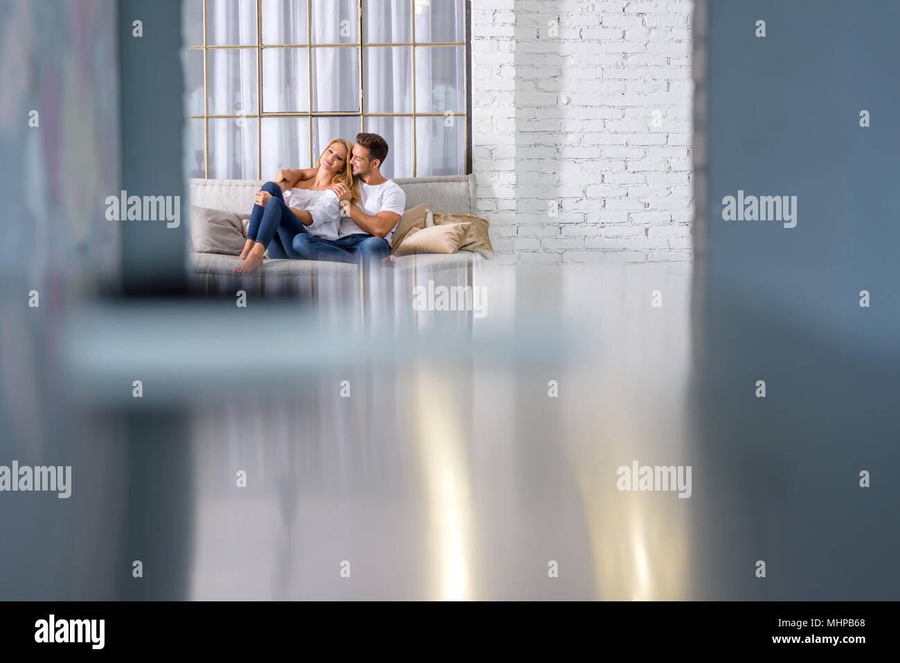 A beautiful young couple sitting on the sofa and cuddling Stock Photo ...