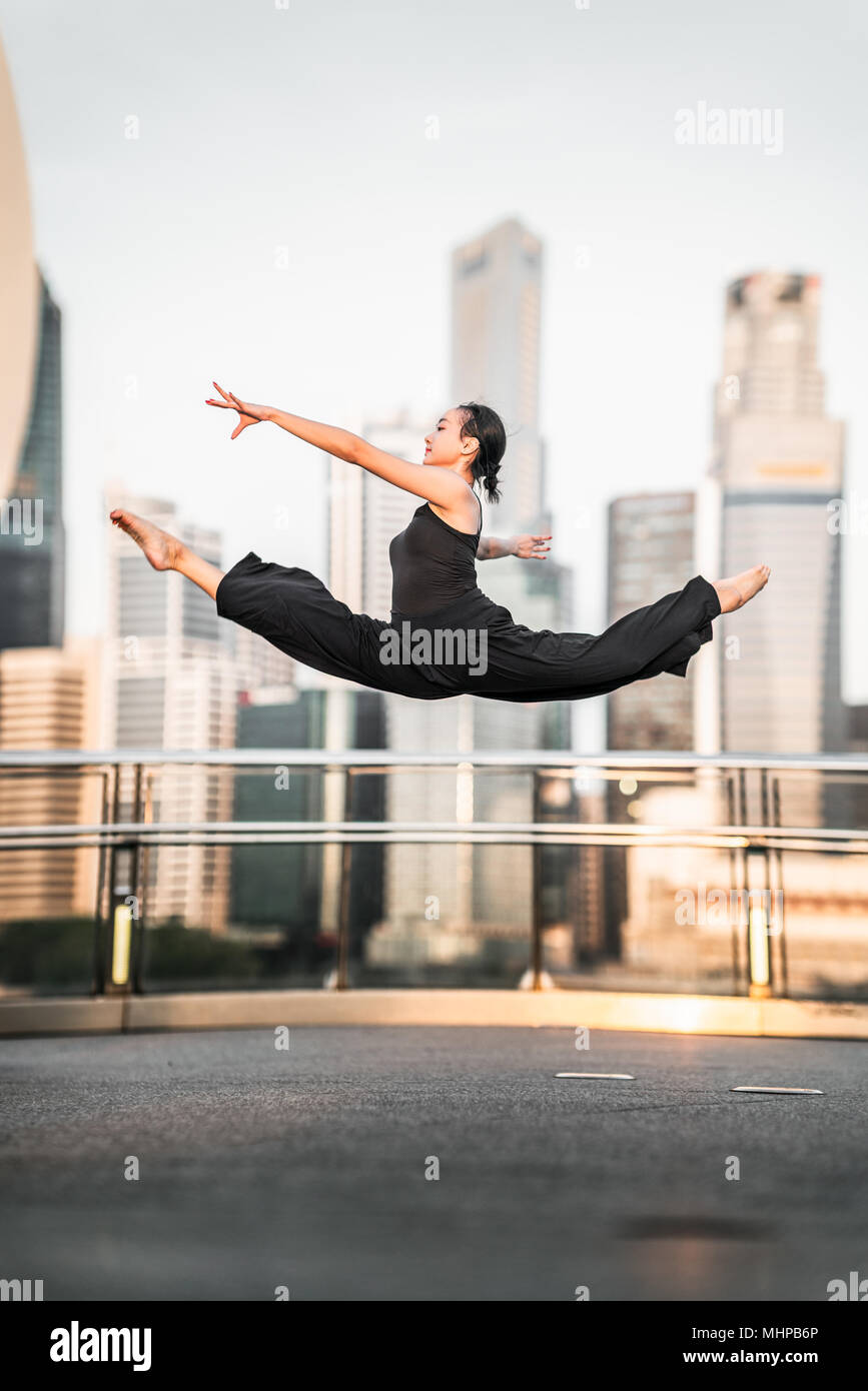 Cute Young woman athlete performs a perfect split leap high up, with ...