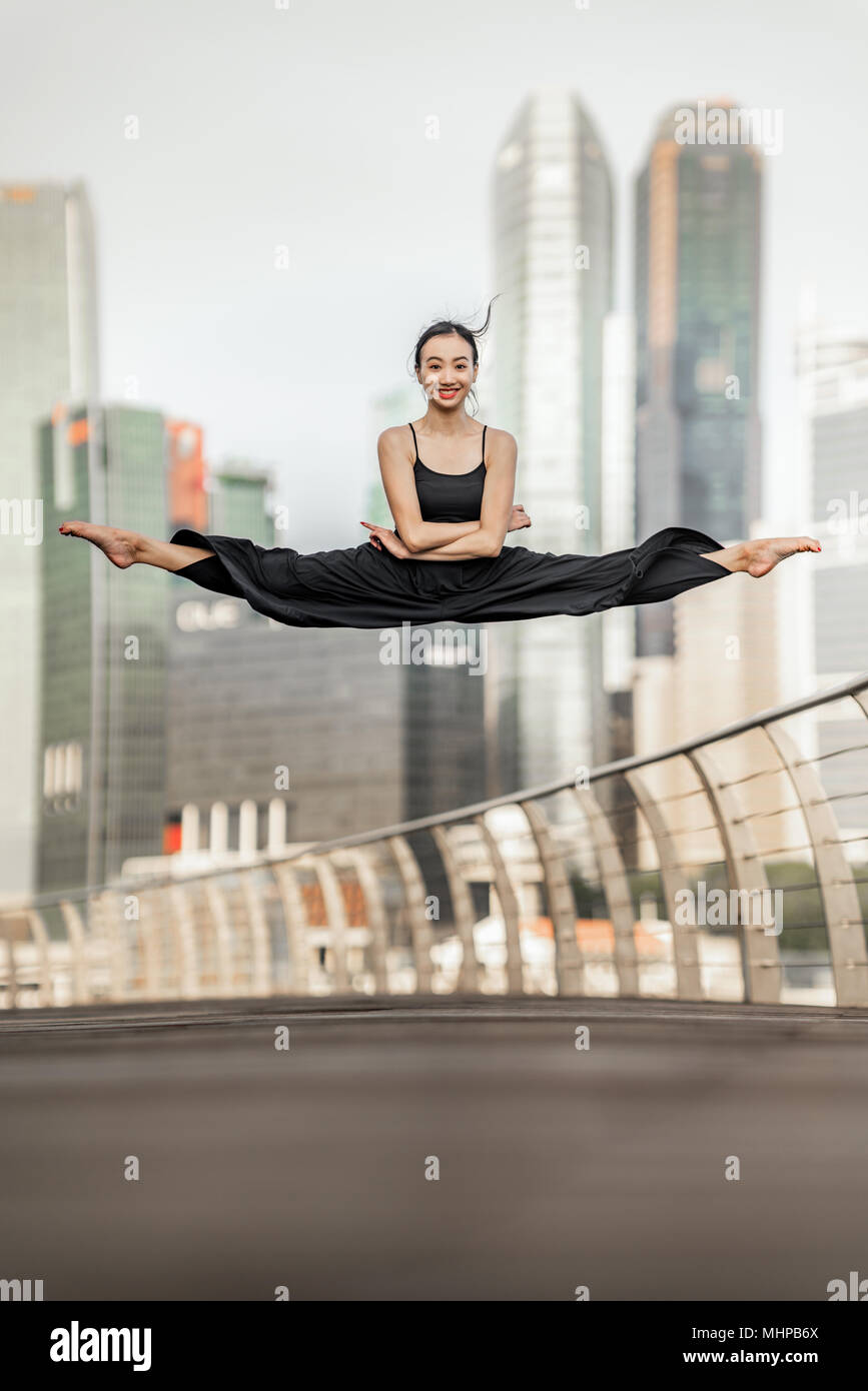 Cute Young woman athlete performs a perfect straddle leap high up, with ...