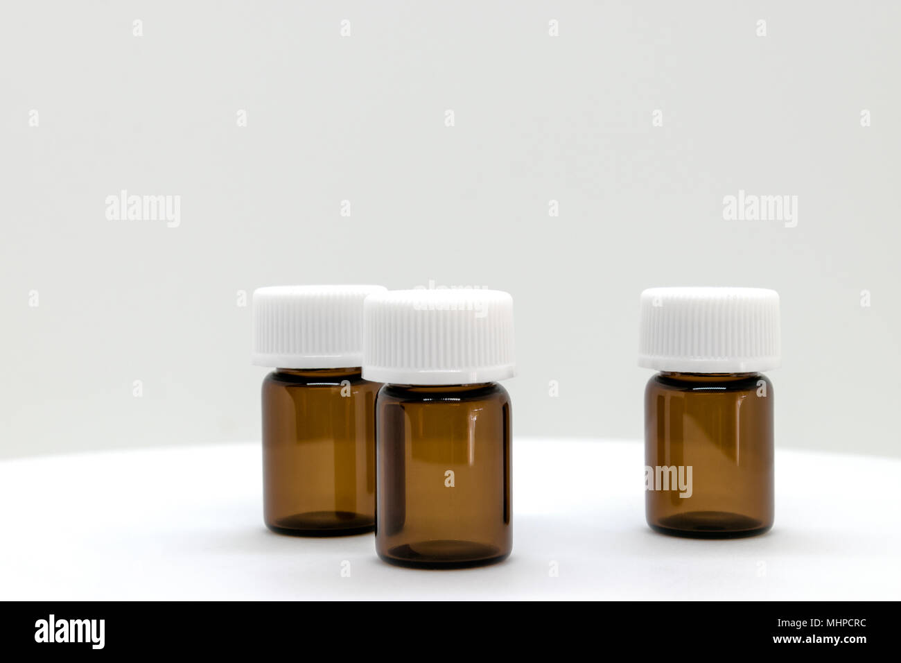 Three brown sample bottles with white caps on white background with ...