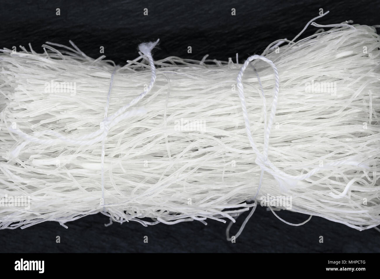 White rice noodles tied with white rope on black stone background ...