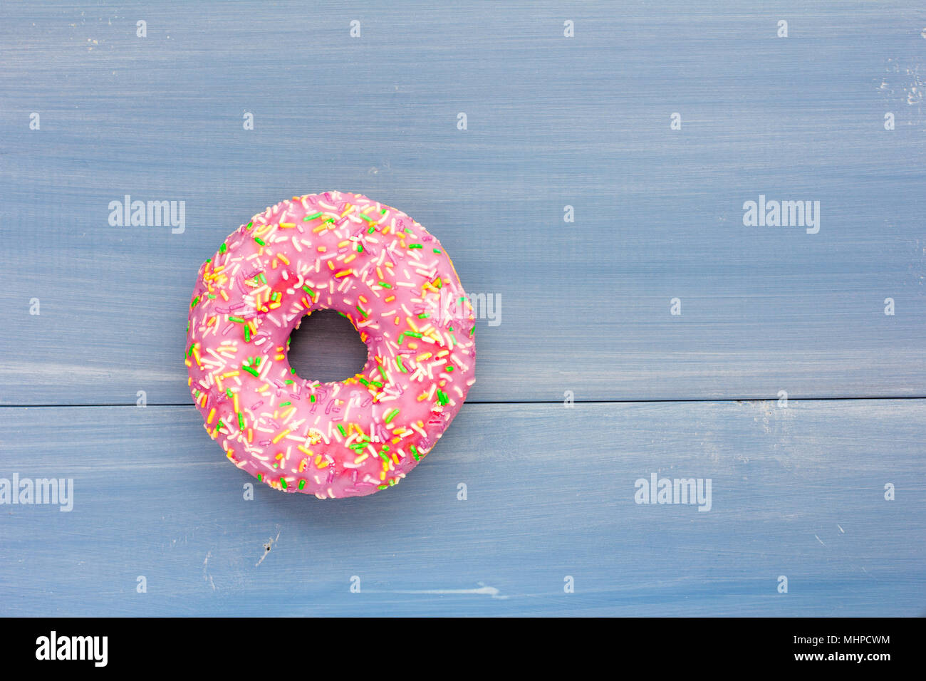 A single donut on blue wooden background Stock Photo - Alamy