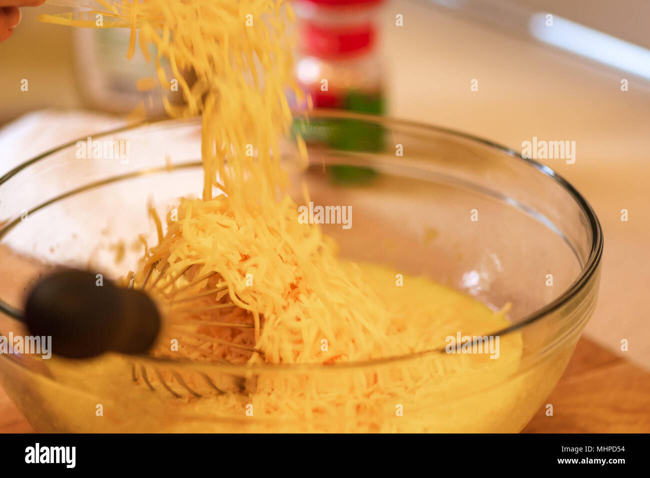 Adding cheese to egg mixture in glass bowl with wisk Stock Photo - Alamy