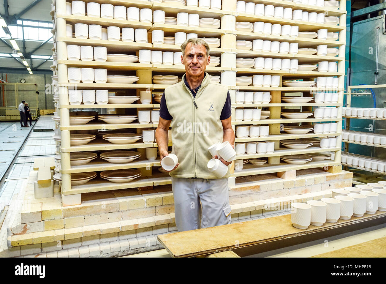 Meissen porcelain factory hall, a man shows porcelain ready for firing ...