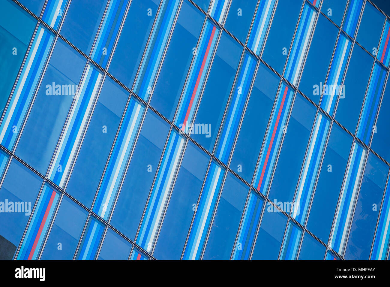 Modern blue glass skyscraper reflects the sky in the bright sunlight ...