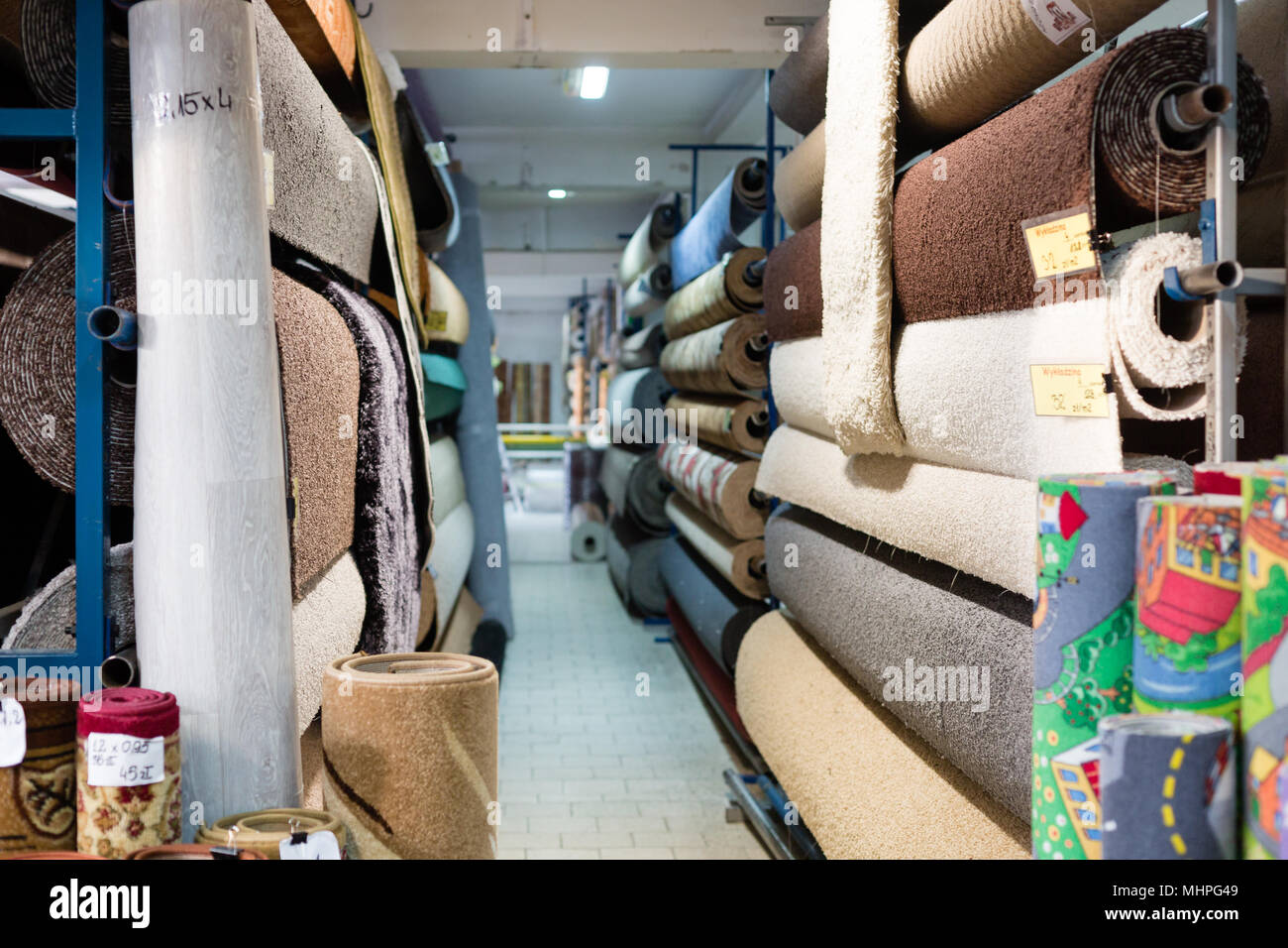 Carpet rolls on a rack in a warehouse Stock Photo - Alamy
