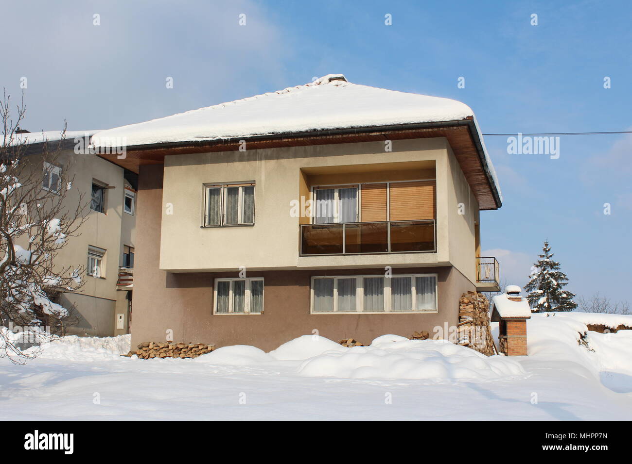 Suburban house surrounded with firewood and freshly fallen deep snow on ...