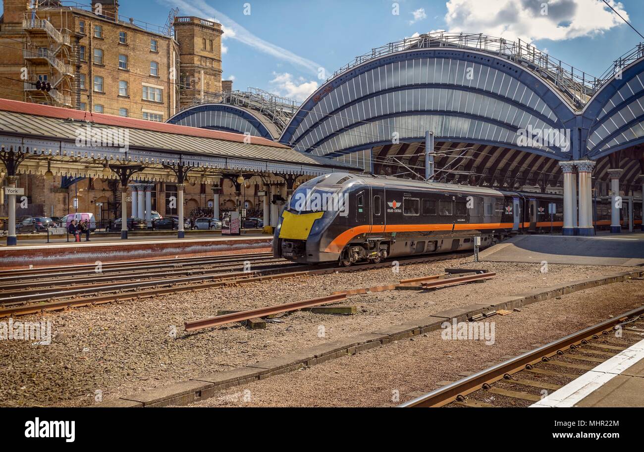 A sleek train engine emerges from an ornate canopy at York Station ...