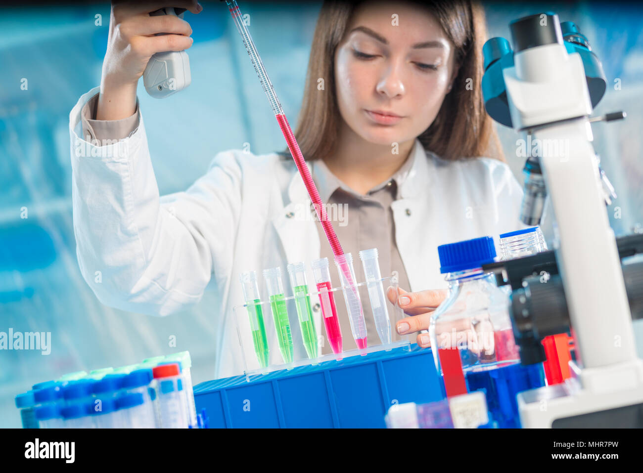 Young woman in scientific lab with pipette and chemicals in test tubes ...