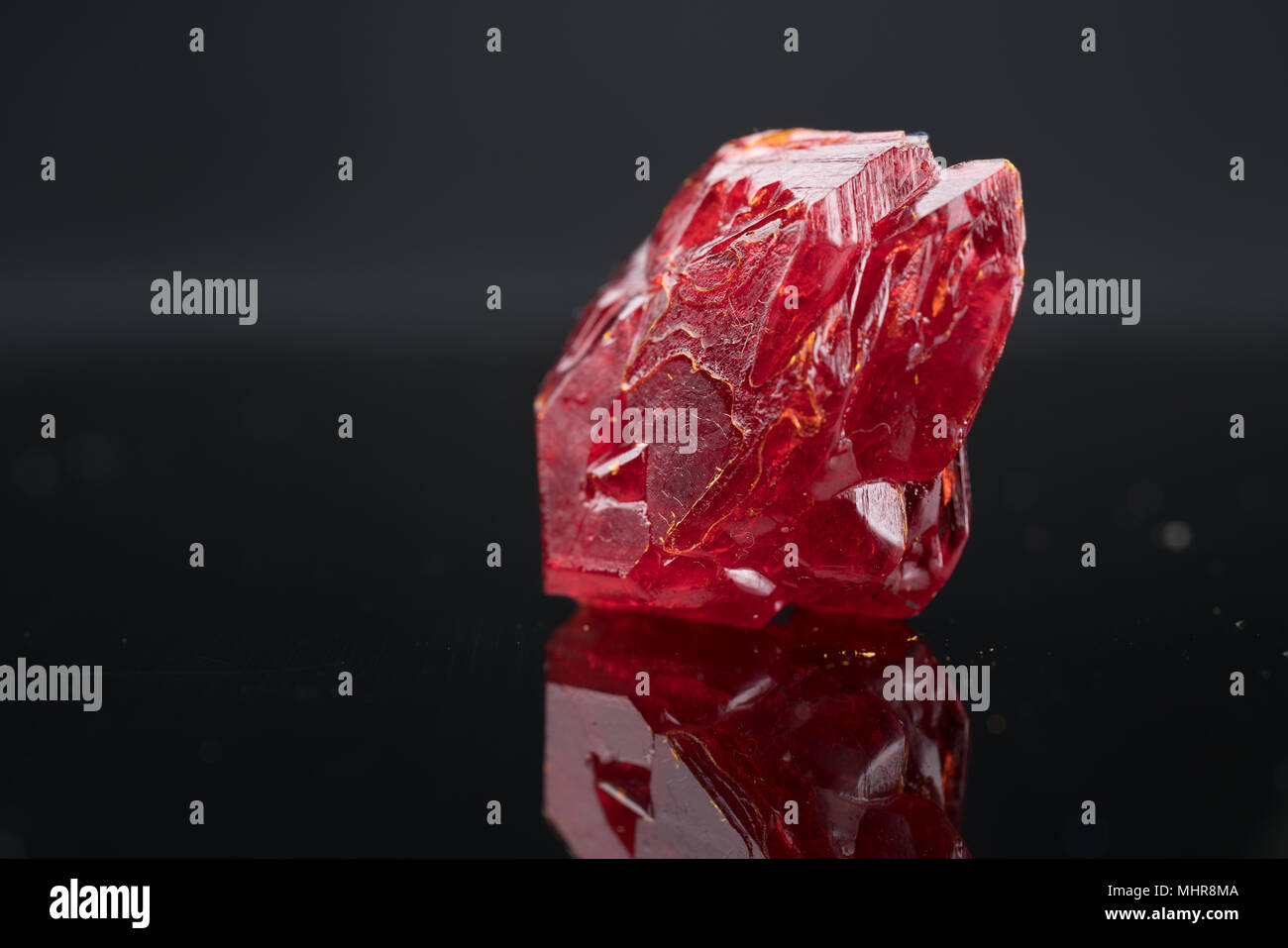 Red natural crystal mineral on a black background Stock Photo - Alamy