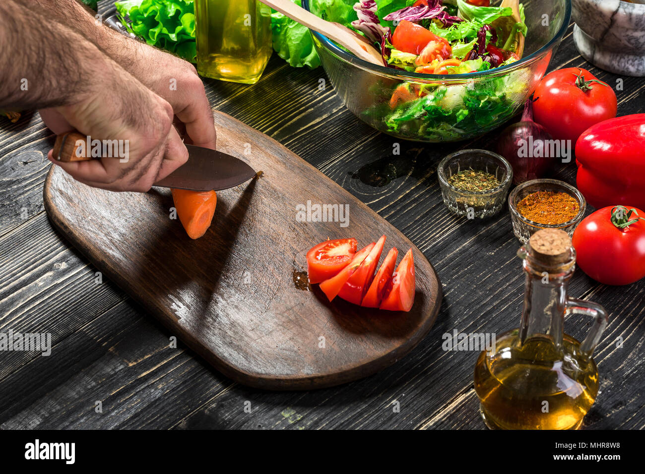 Chef man cooking in the kitchen. Man's hand cuts carrot on a wooden ...