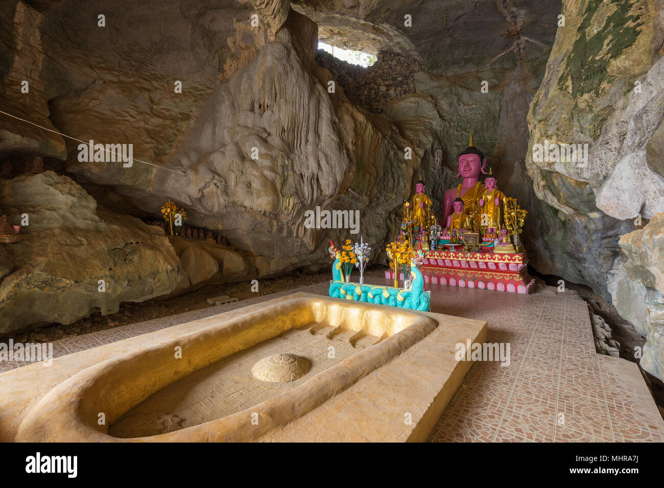Buddha's footprint and several Buddha statues on altar inside the Tham ...