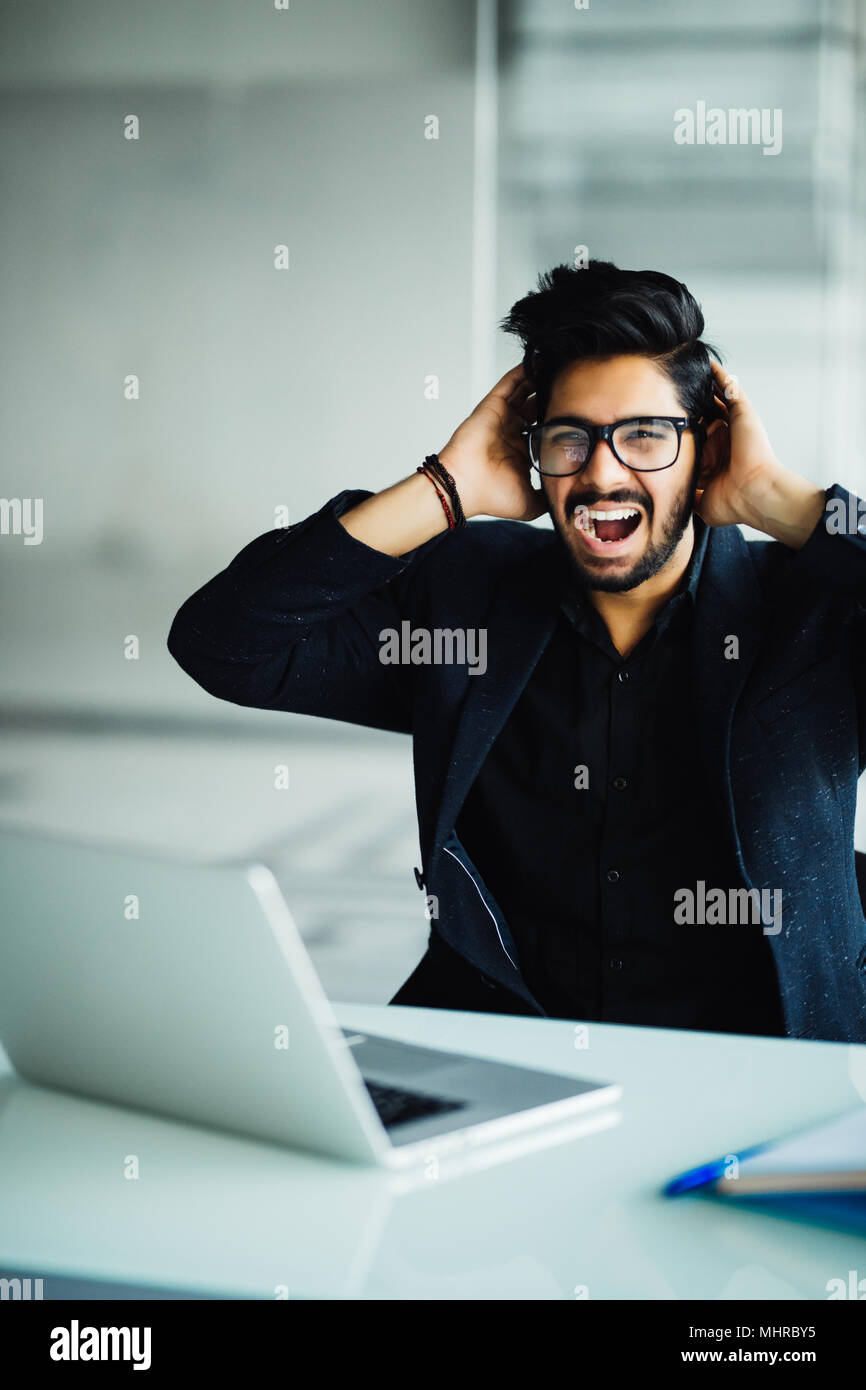 Angry businessman shaking his laptop computer and yelling in fury as he ...