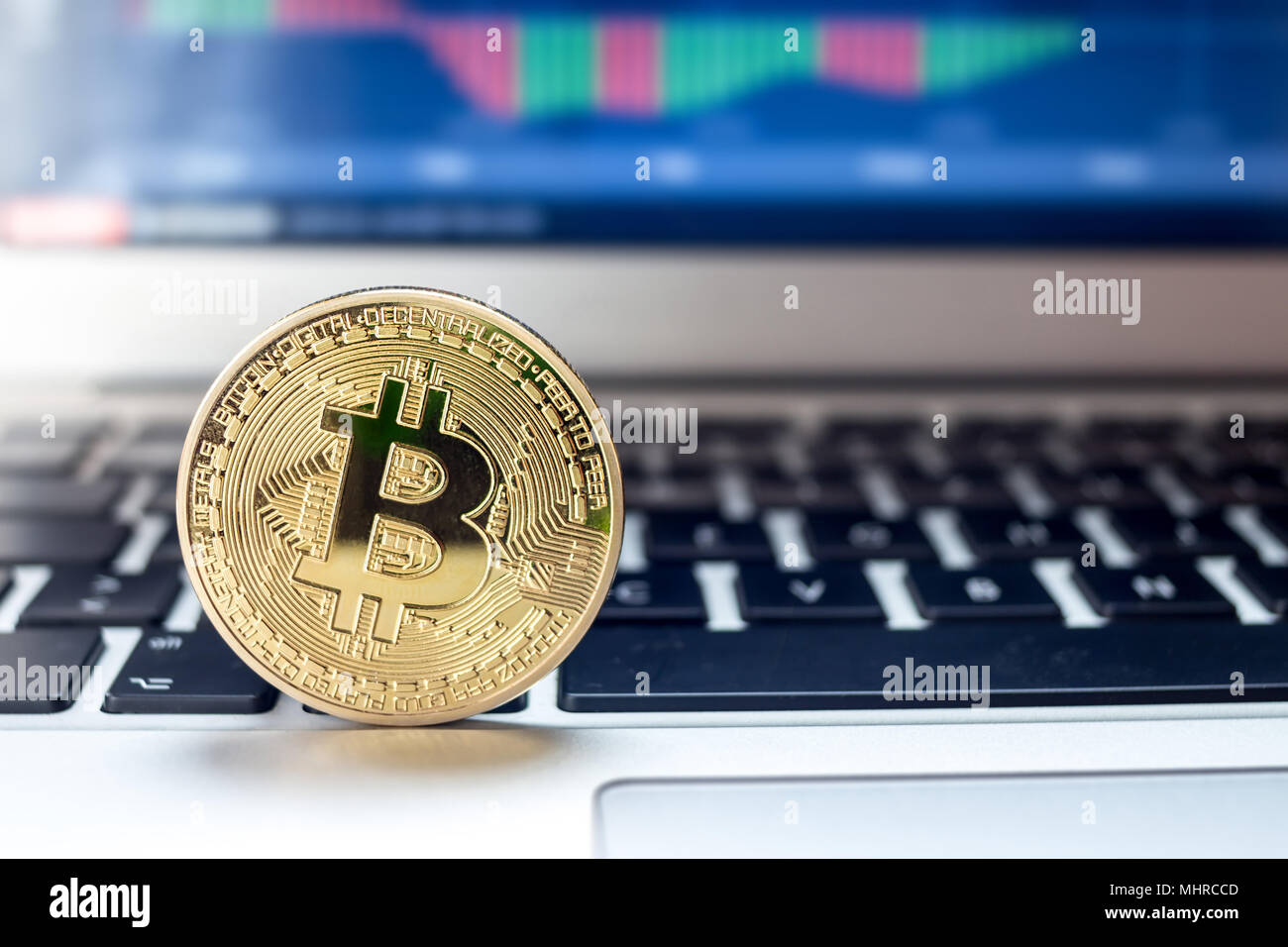 Physical Bitcoin placed on Laptop computer with charts on screen Stock ...