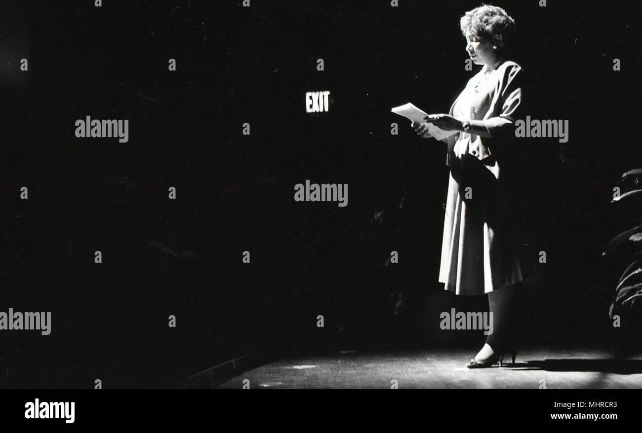 Snapshot of a woman on stage, reading a script Stock Photo - Alamy