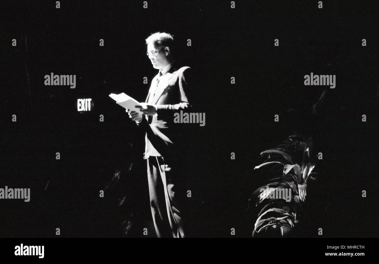 Snapshot of a man on stage, reading a script Stock Photo - Alamy