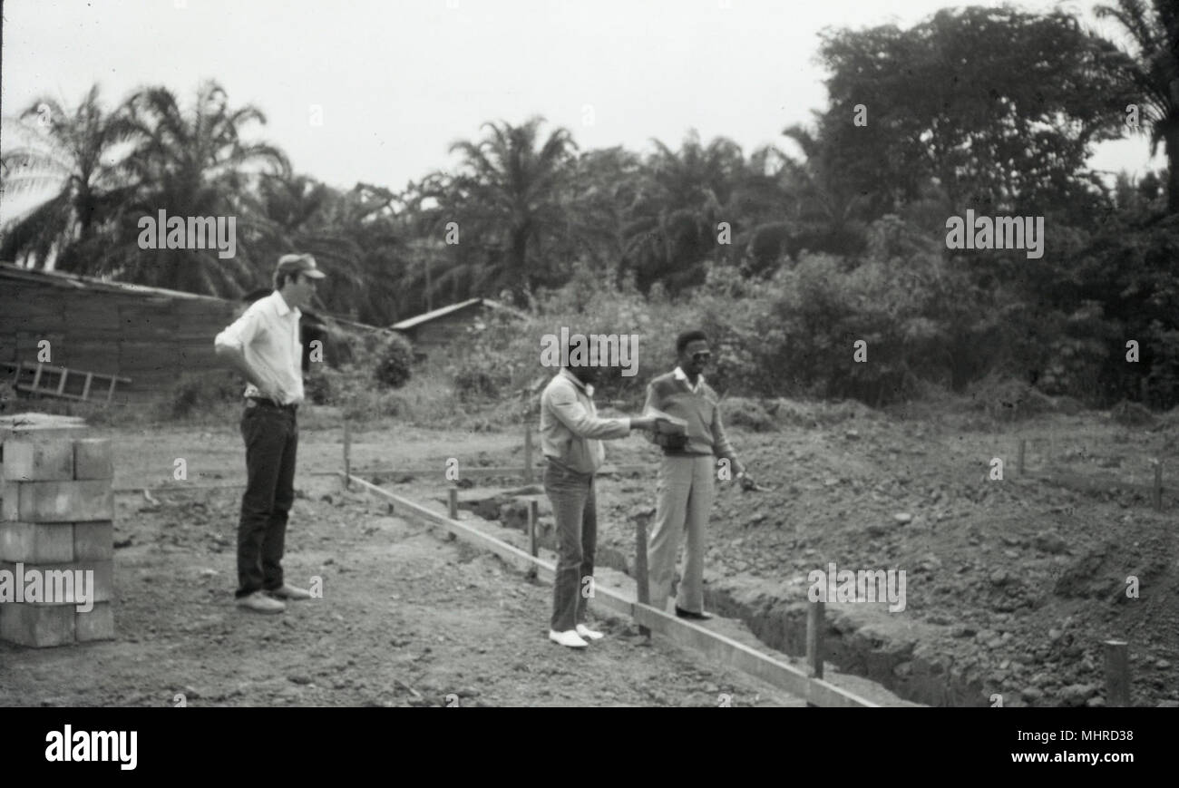 Snapshot of men standing in the soon-to-be foundation of a structure ...