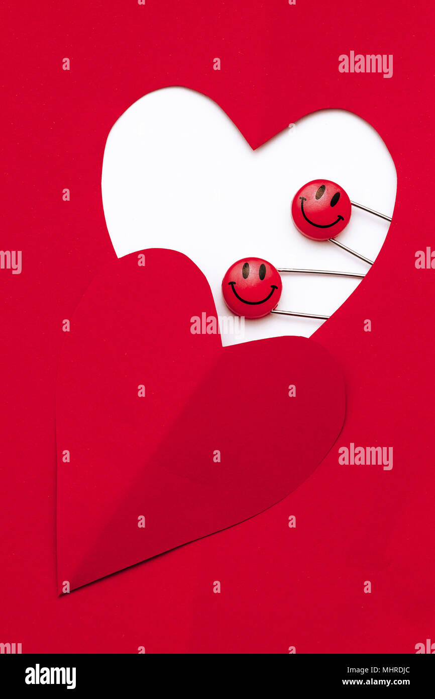 Plastic head metal safety pins pinned in heart shaped paper. Red smile ...