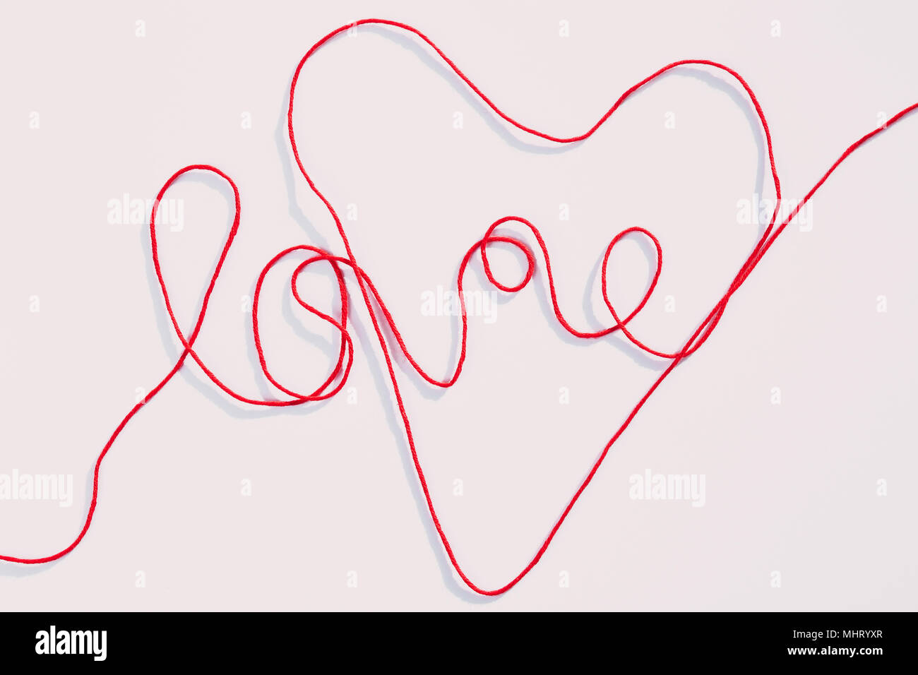 Word love and heart shape written with red yarn thread isolated on ...