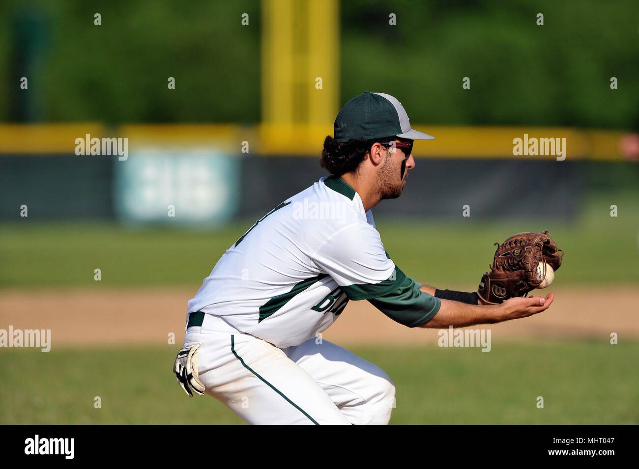 Third baseman fielding a ground ball prior to throwing on to first base ...