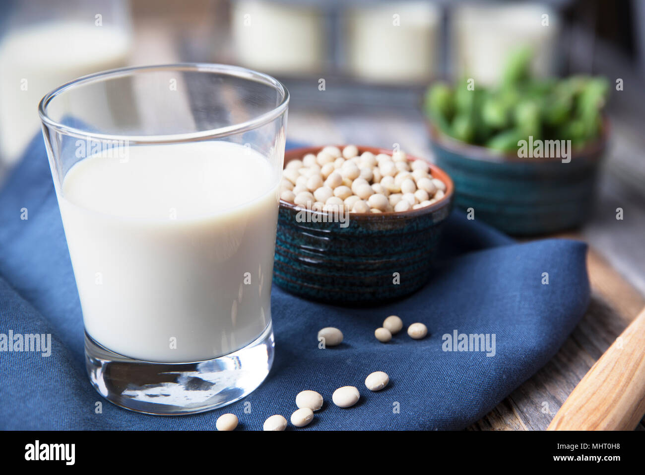 Glass of soy milk with soybeans and edamame pods in the background ...