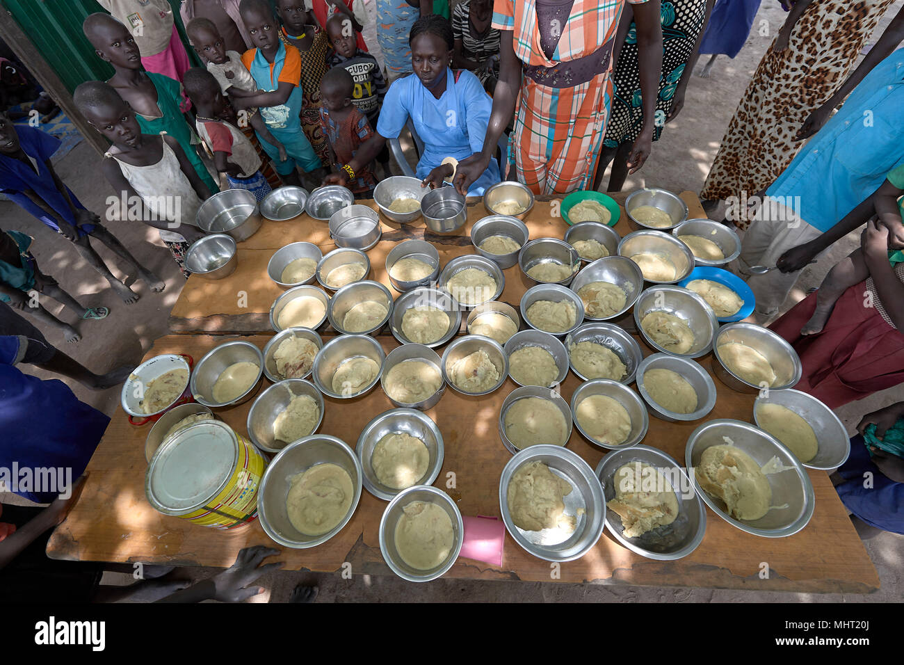 Kana Achot fills bowls with food in an emergency feeding program for ...