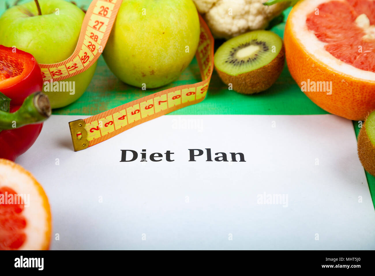 Food and sheet of paper with a diet plan on a green wooden background ...