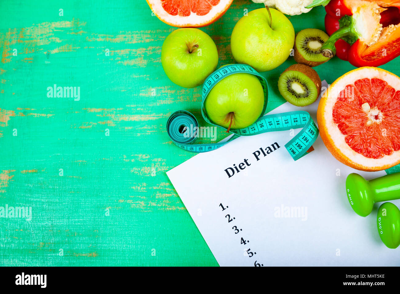 Food and sheet of paper with a diet plan on a green wooden background ...