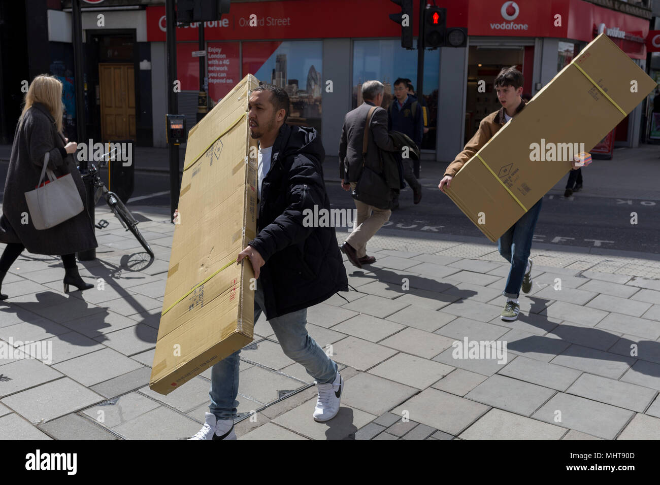 Two men carry awkward, long boxes along Oxford Street, on 1st May, in ...