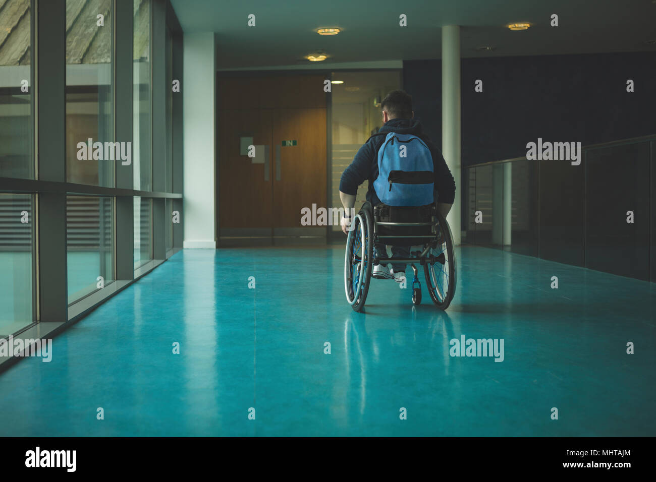 Handicapped man on wheelchair moving in passage Stock Photo - Alamy