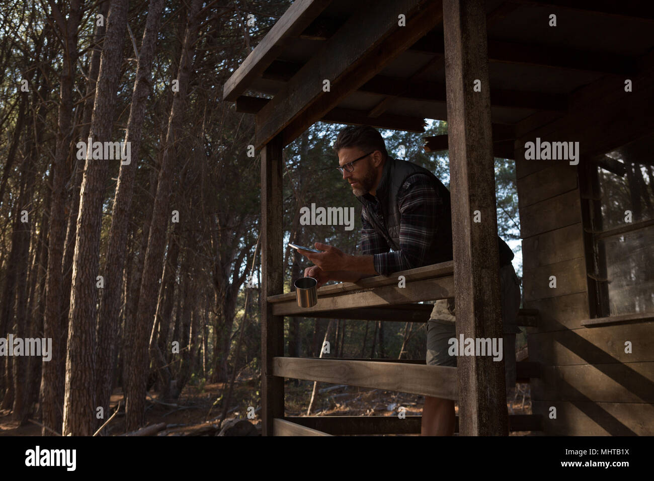Man using mobile phone in cabin porch Stock Photo - Alamy