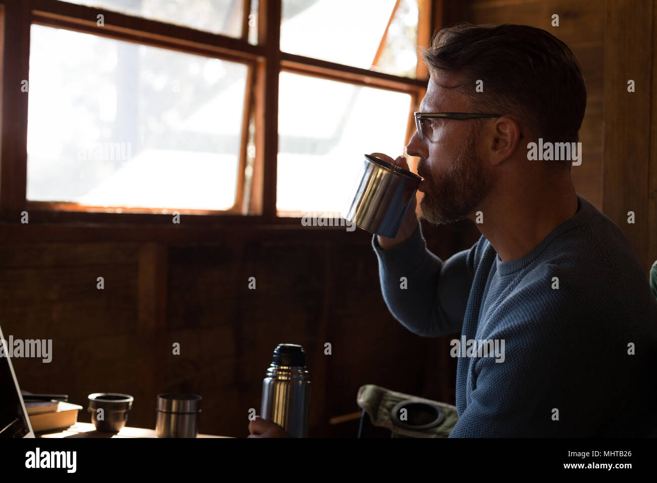 Man with coffee mug looking through window Stock Photo - Alamy